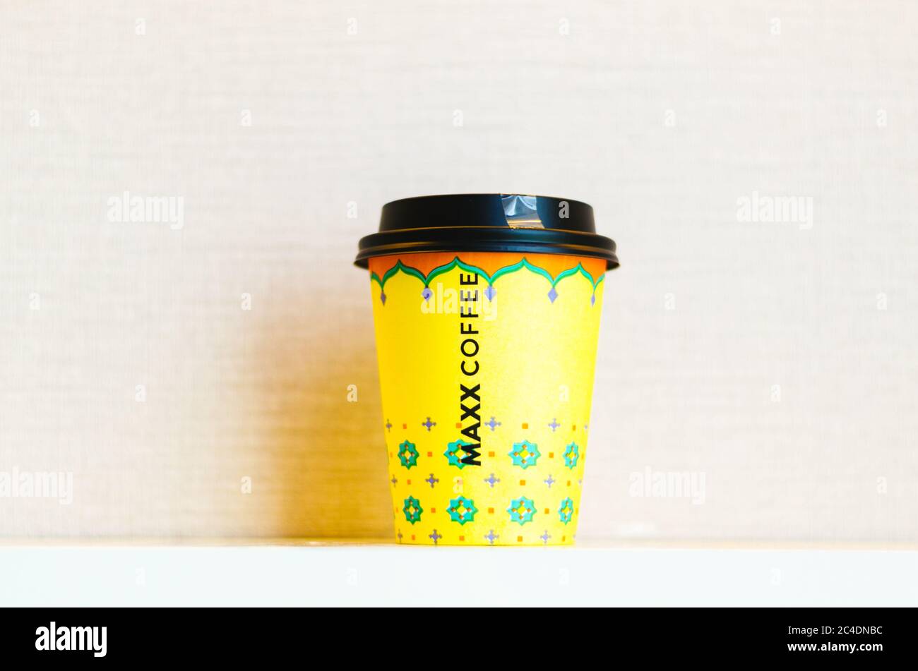 A yellow take away cup of coffee with the Maxx Coffee chain name ...
