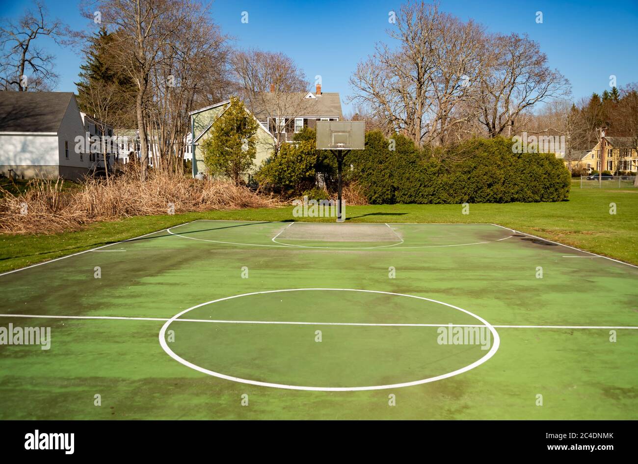 green recreational basketball court in a park with houses in background ...