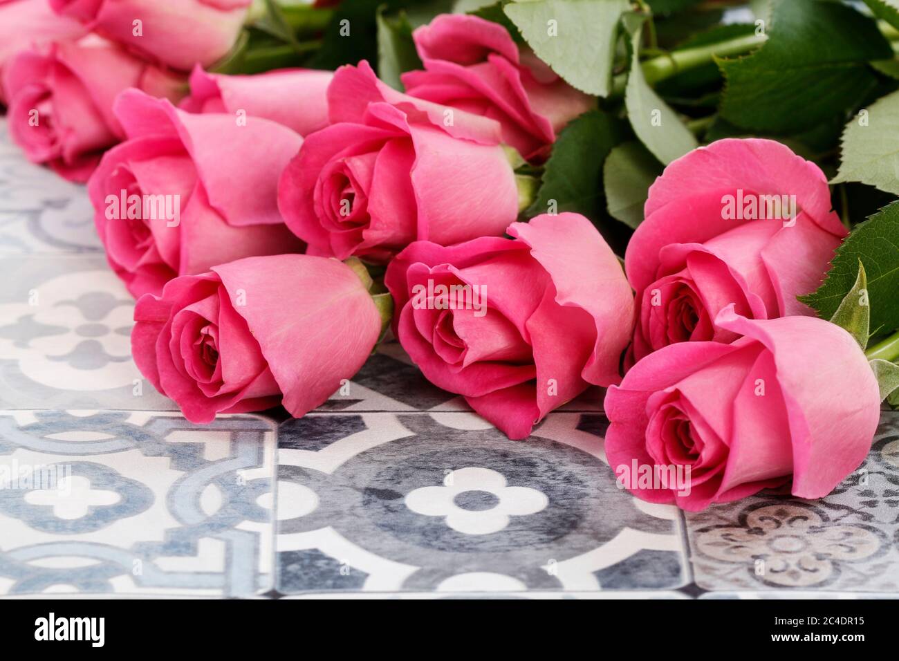 Romantic pink roses are lying on beautiful spanish floor tiles. Party ...