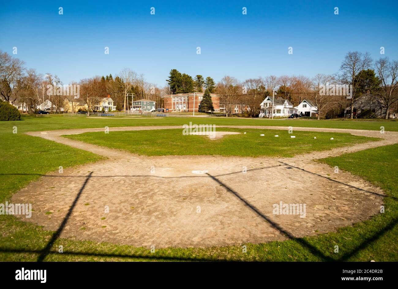 green recreational baseball field in a park with houses in background ...