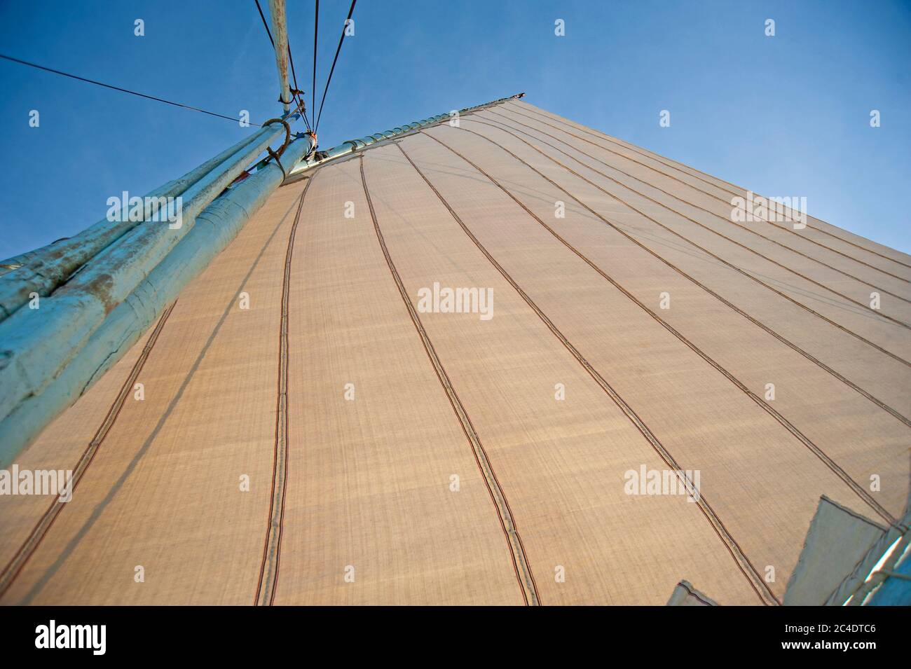 Abstract view of wooden sailing boat mast with rigging on blue sky ...