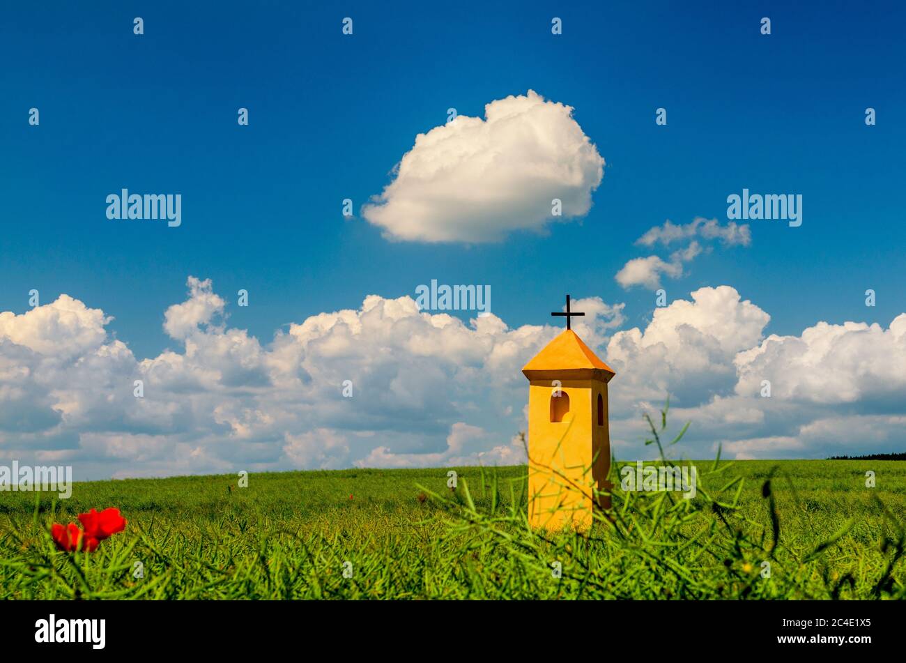 Yellow tower with a cross on top surrounded by a large green landscape ...