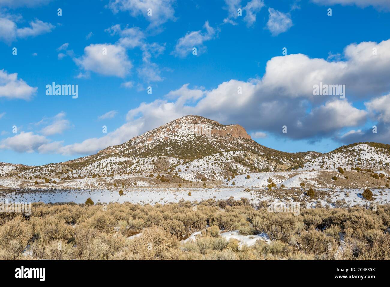 A winter Utah landscape, with snow on a mountain and a blue sky ...
