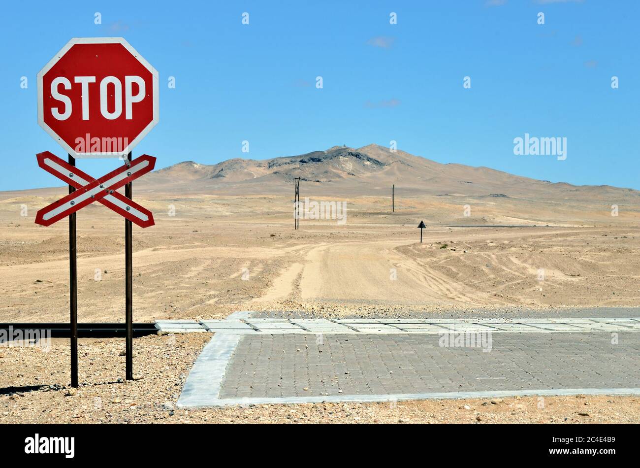 Dirt country road in Namib desert. There are railroads across the road ...