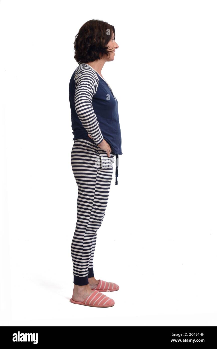 side view of a woman in pajamas on white background, hands on hip and ...