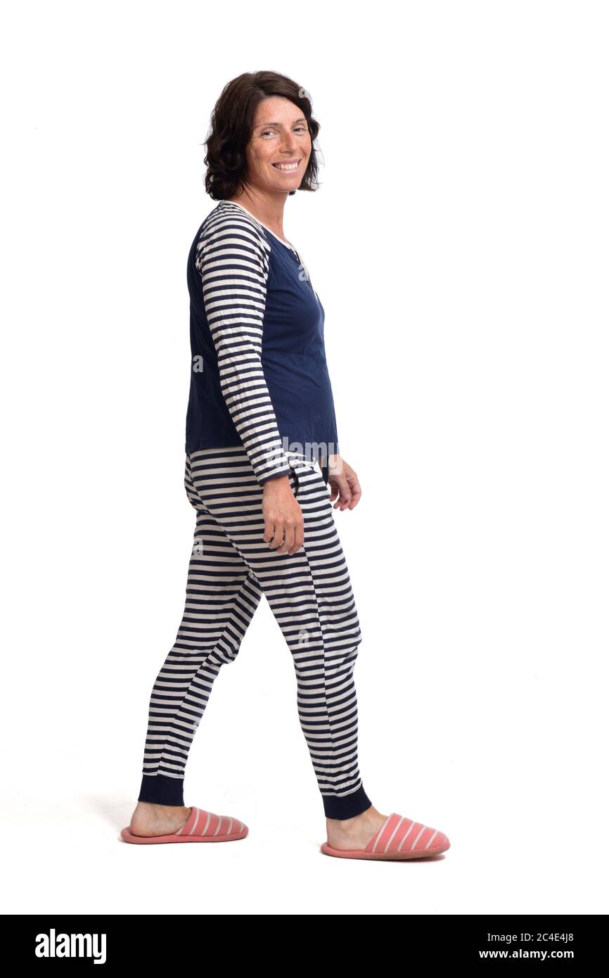 side view of a woman in pajamas walking on white background and looking ...