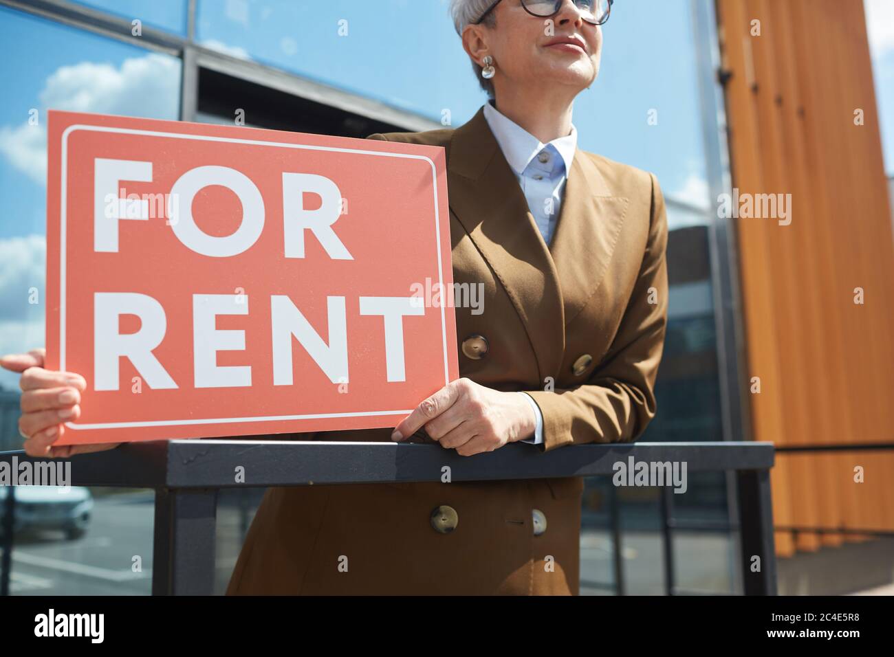 Close-up of real estate agent with placard For Rent standing outdoors ...