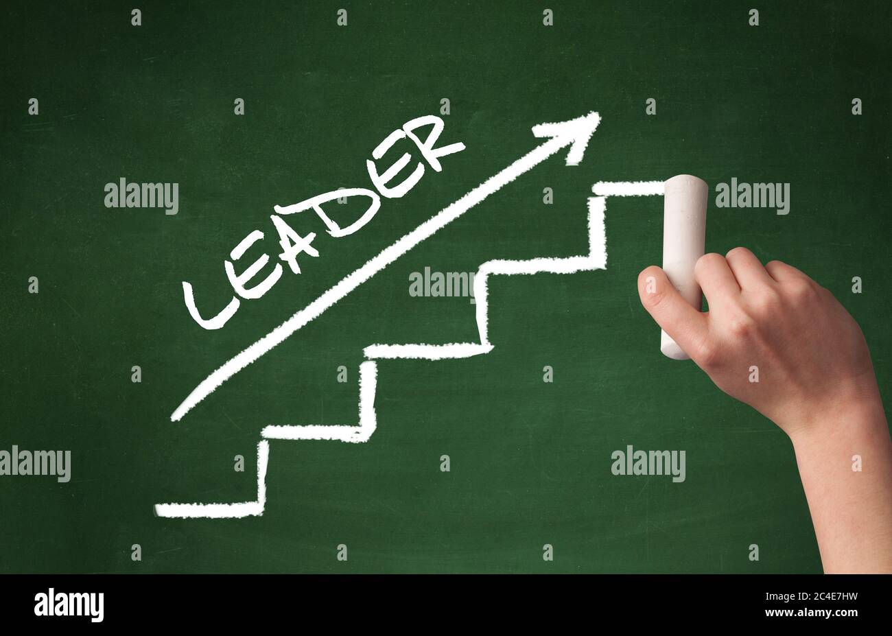 Hand drawing LEADER inscription with white chalk on blackboard ...