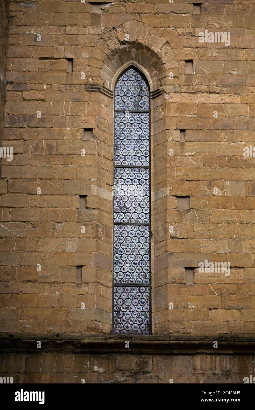Old stained-glass window in vertical narrow window of ancient brick ...