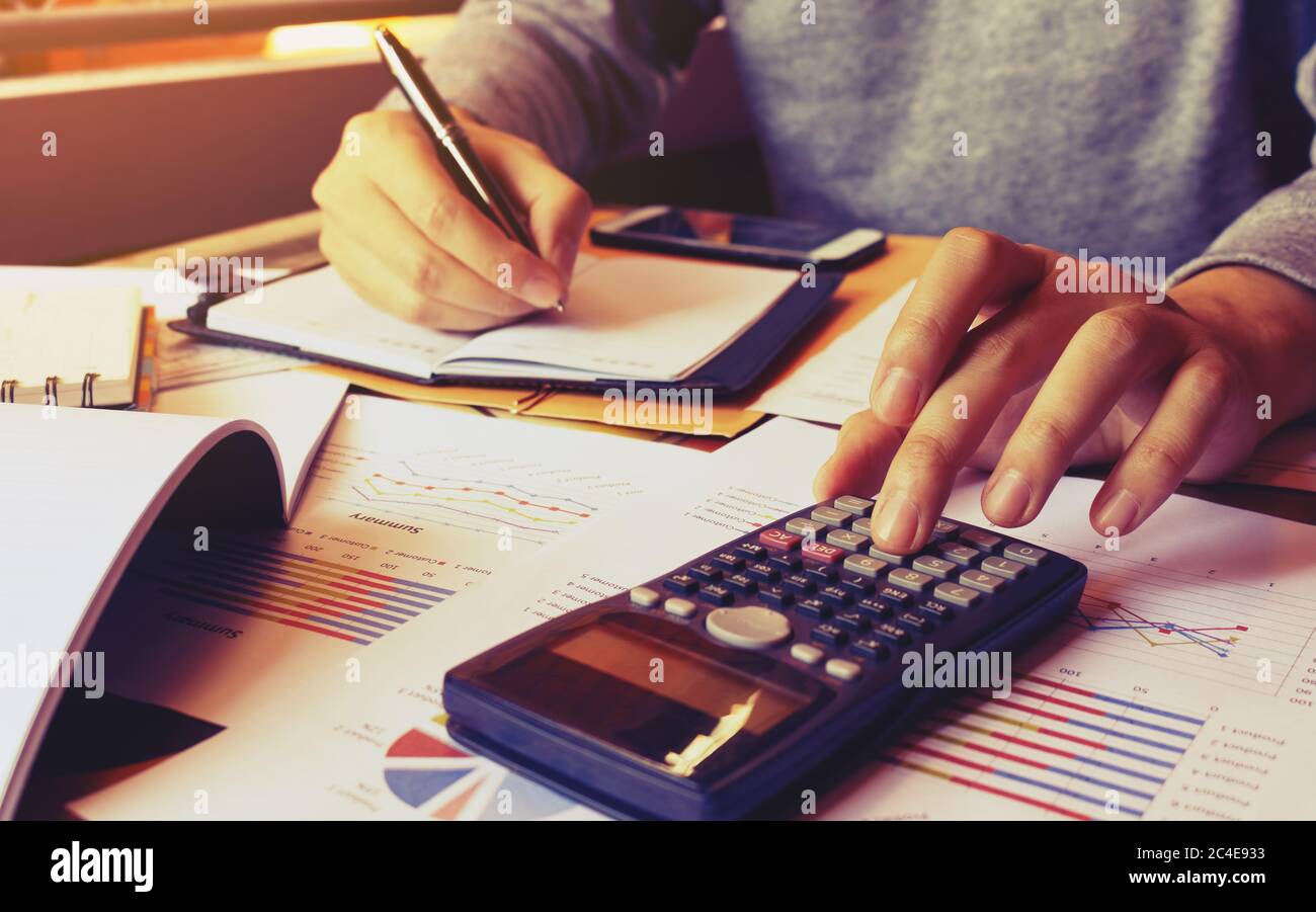 Young man using calculator and writing note and calculate finance at ...