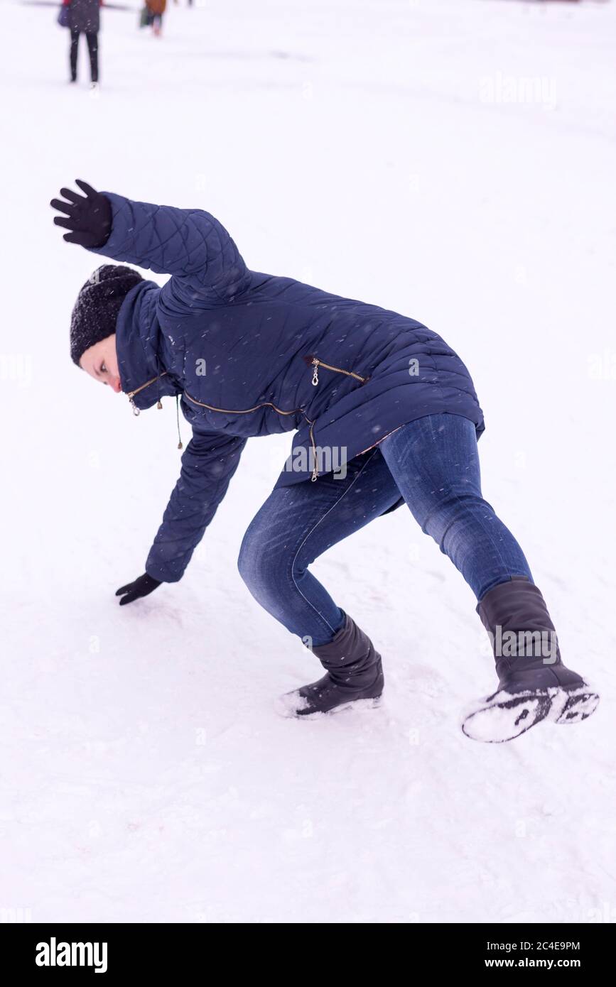 The girl slipped on ice covered with snow in the street, falling and ...