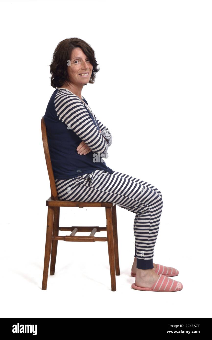 side view of a woman in pajamas sitting o a chair on white backgroun ...