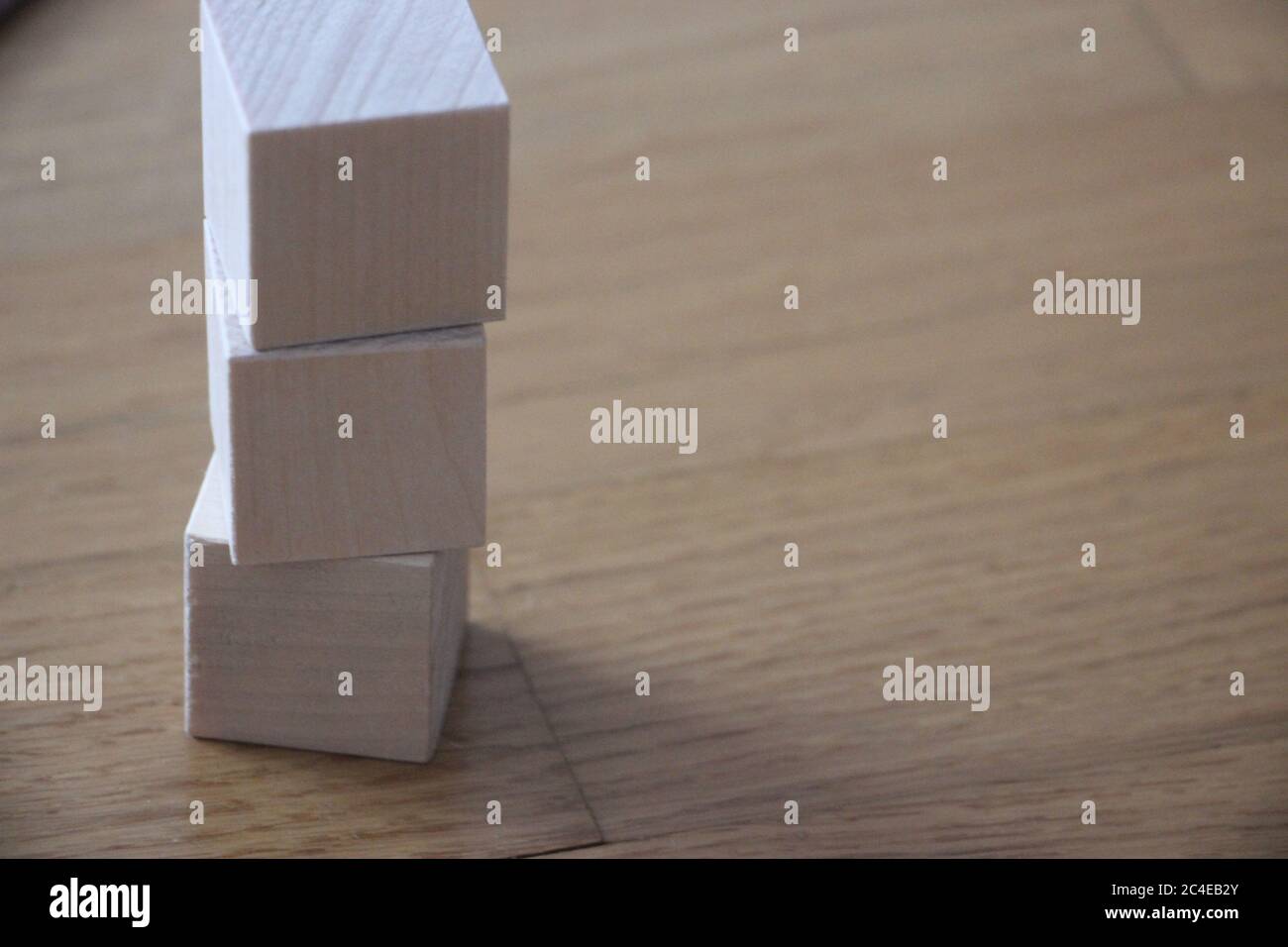 Three wooden cubes pt vertically on table background Stock Photo - Alamy