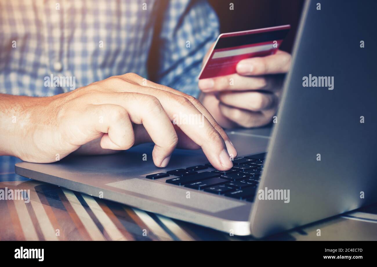 Man's hand typing on keyboard laptop and holding debit card for ...