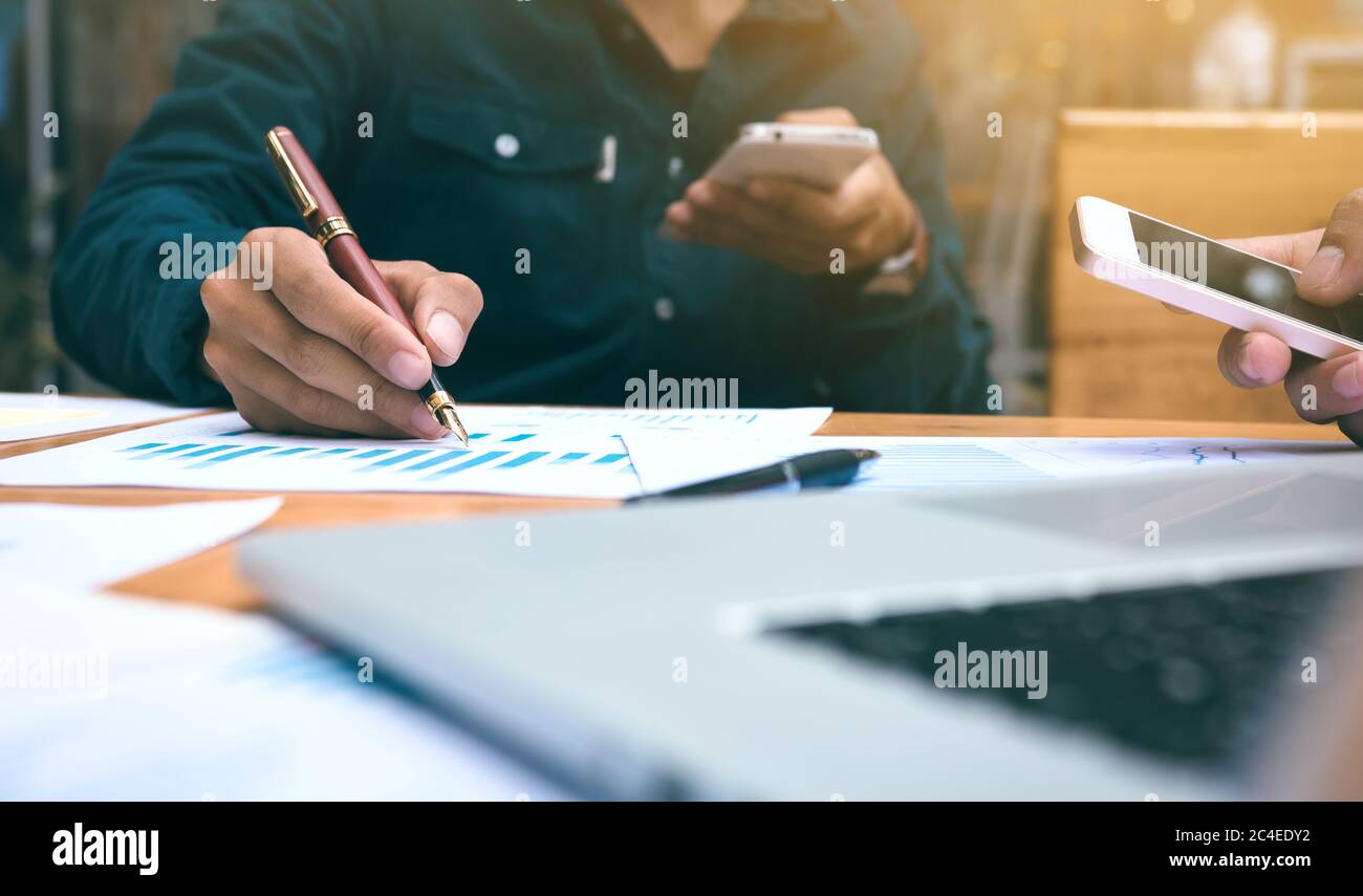 Businessman writing or pointing summary report chart and using smart ...