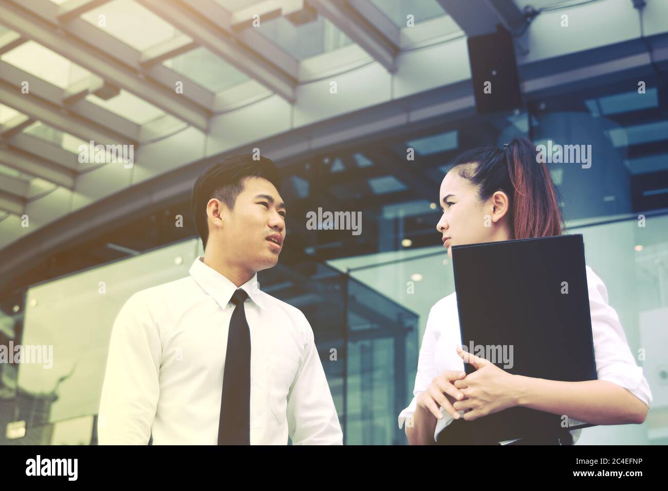 Two business asian people standing in front of office building and ...