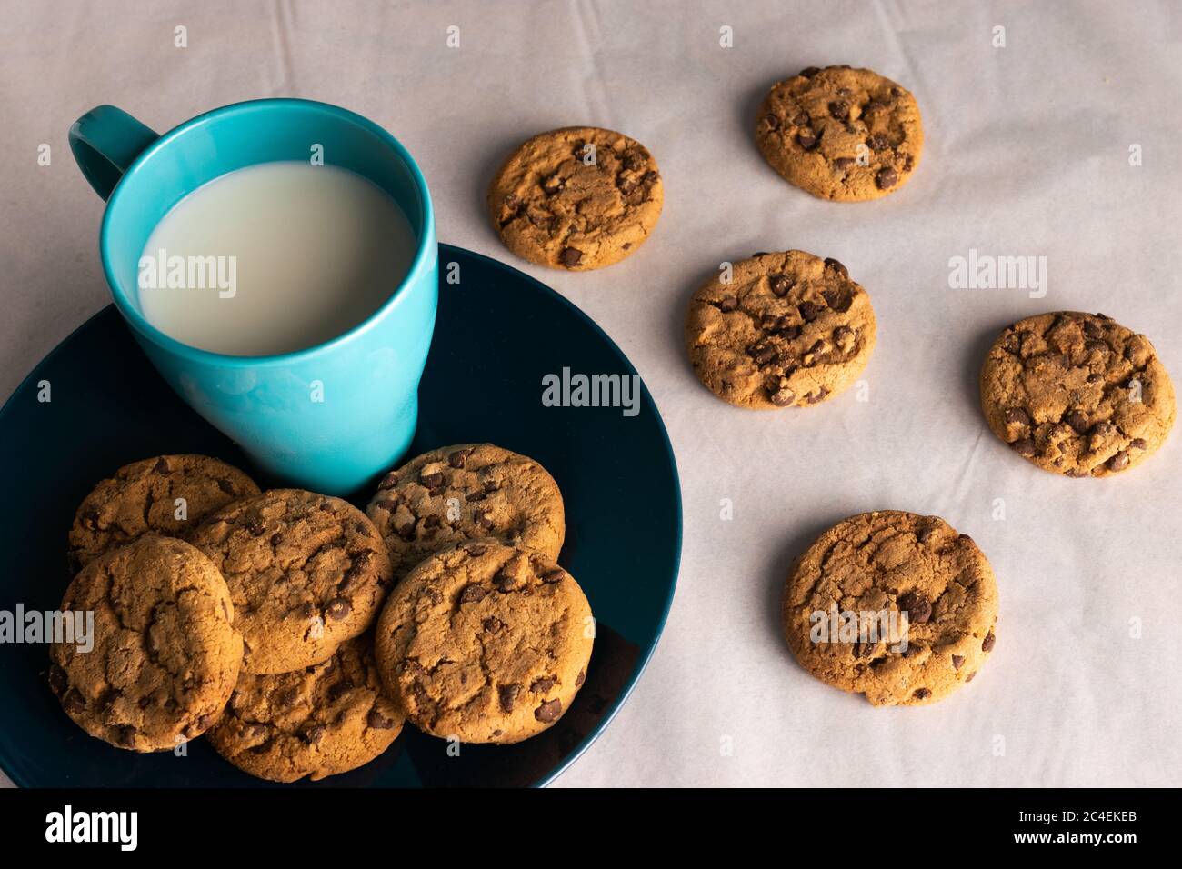 Landscape shot of a blue mug of milk and chocolate chip cookies around ...