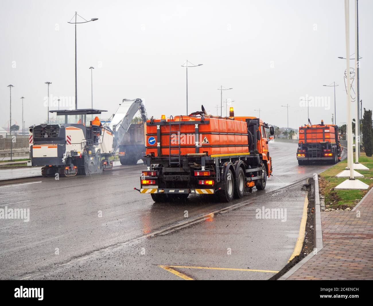 The road miller removes the asphalt from the road and the watering ...