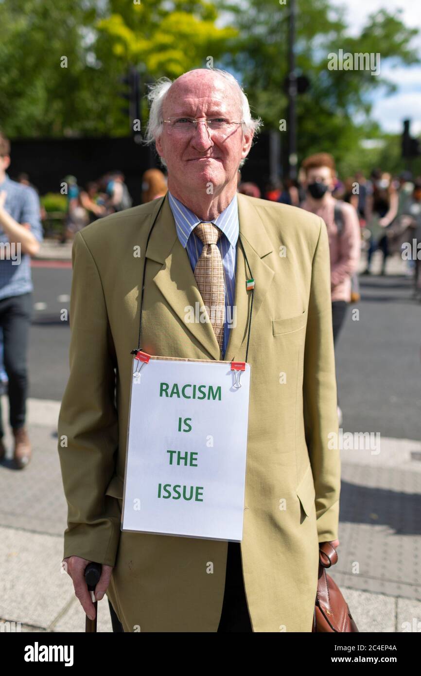 Portrait of an elderly man wearing a protest sign around his neck, at a ...
