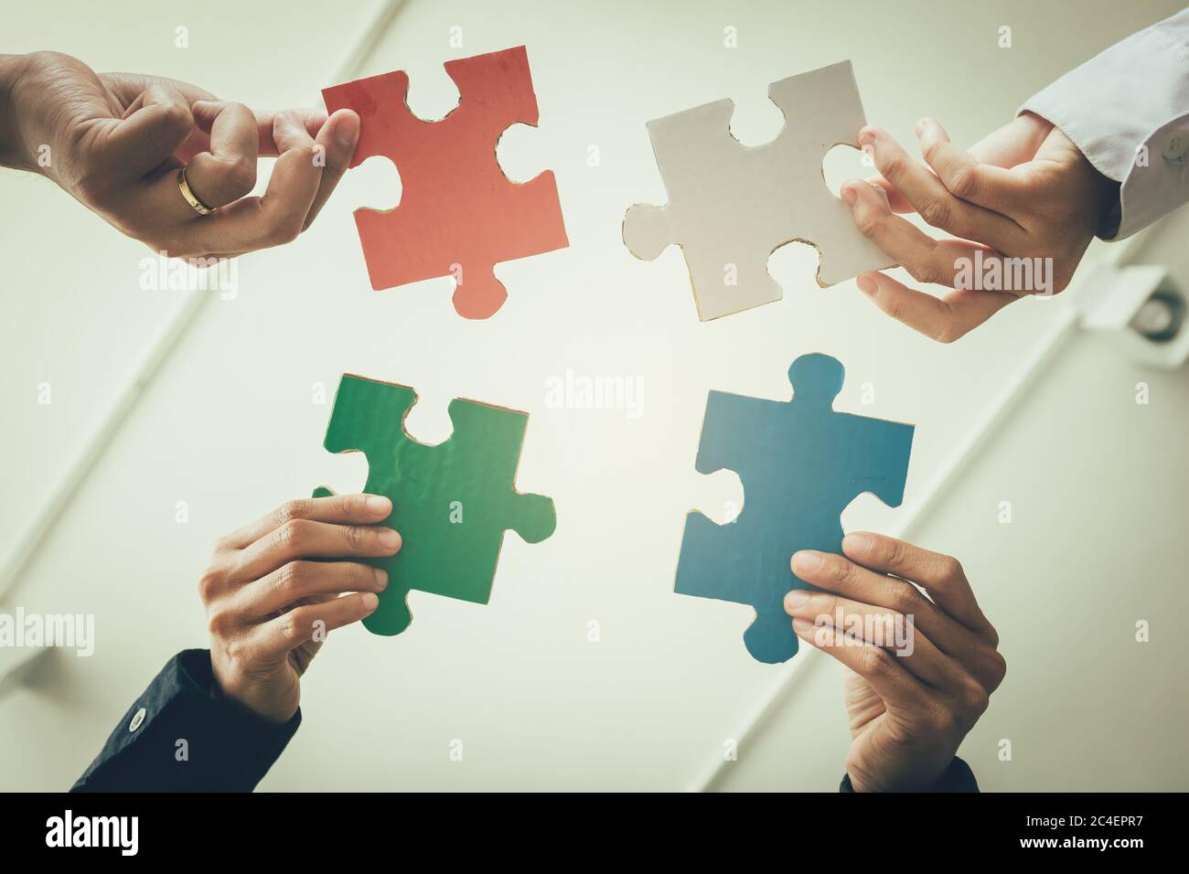 Multi-ethnic group of business professional putting four puzzle pieces ...