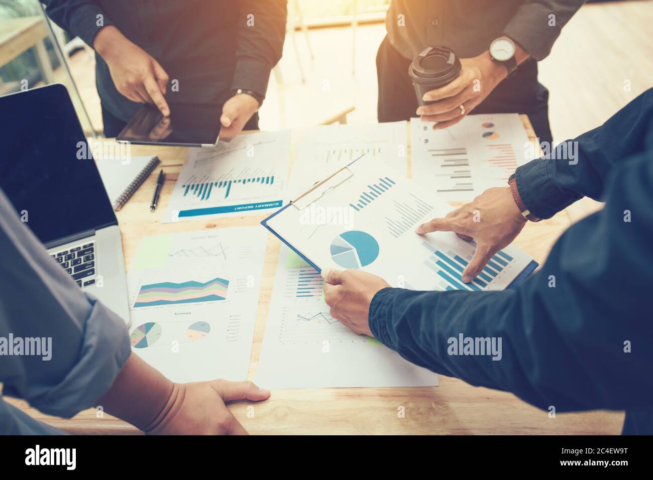 Business people pointing graph sheets on table during discussion of ...
