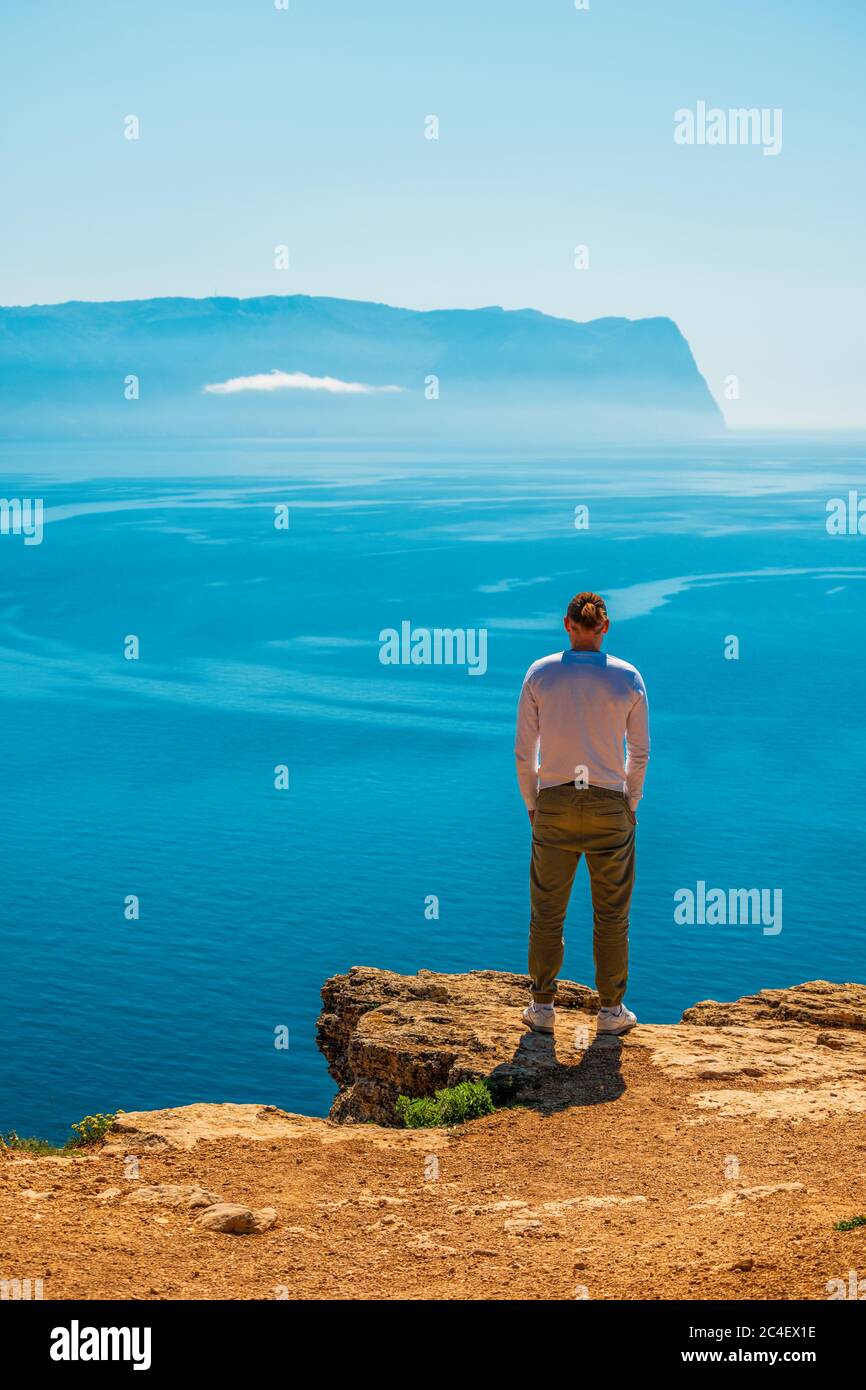 Back view man standing on cliff looking to sea hi-res stock photography ...