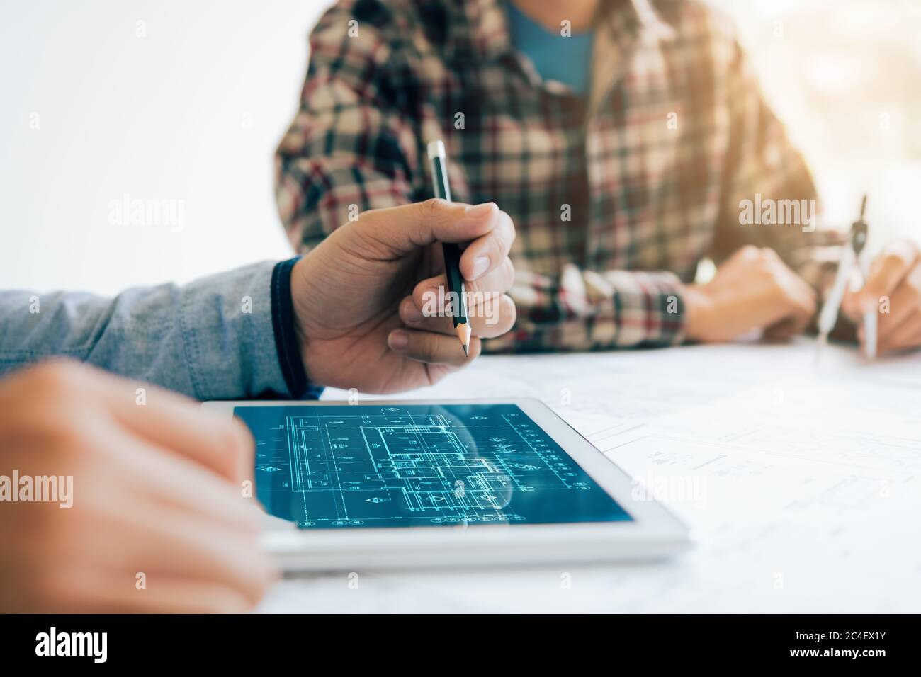 Male architect using digital tablet with architectural plan on table ...