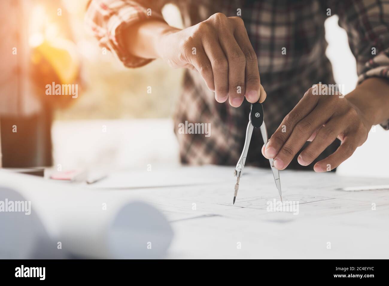 Close up of an architect's hands using a drawing compass on a blueprint ...