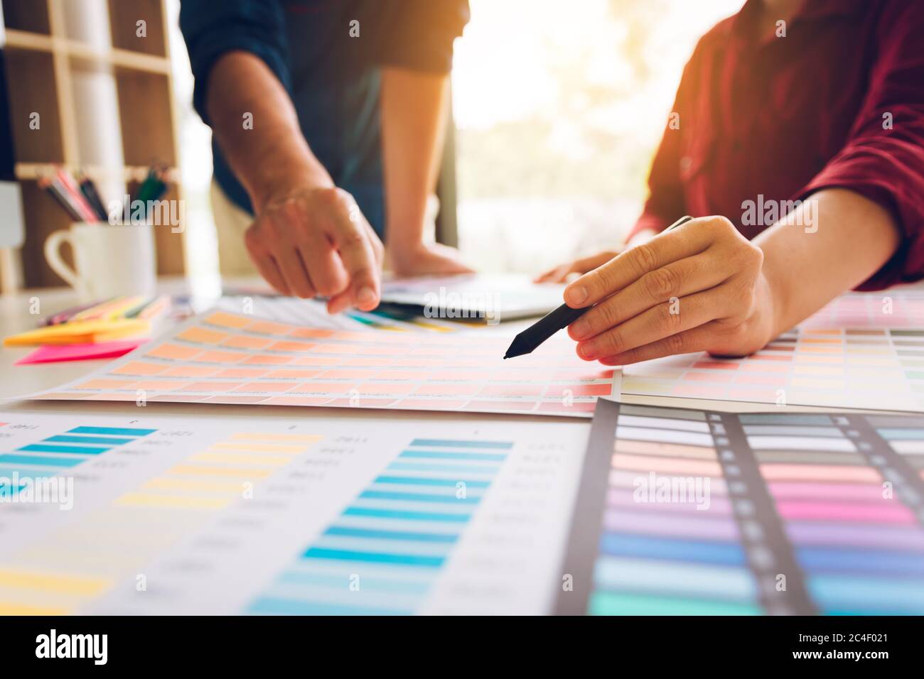 Asian designer working at his desk and is choosing colors together ...