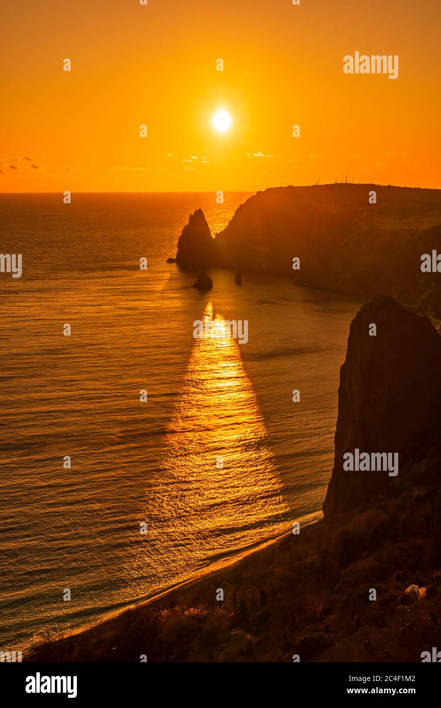 A red burning sunset with the silhouette of a cliff over the sea Stock ...