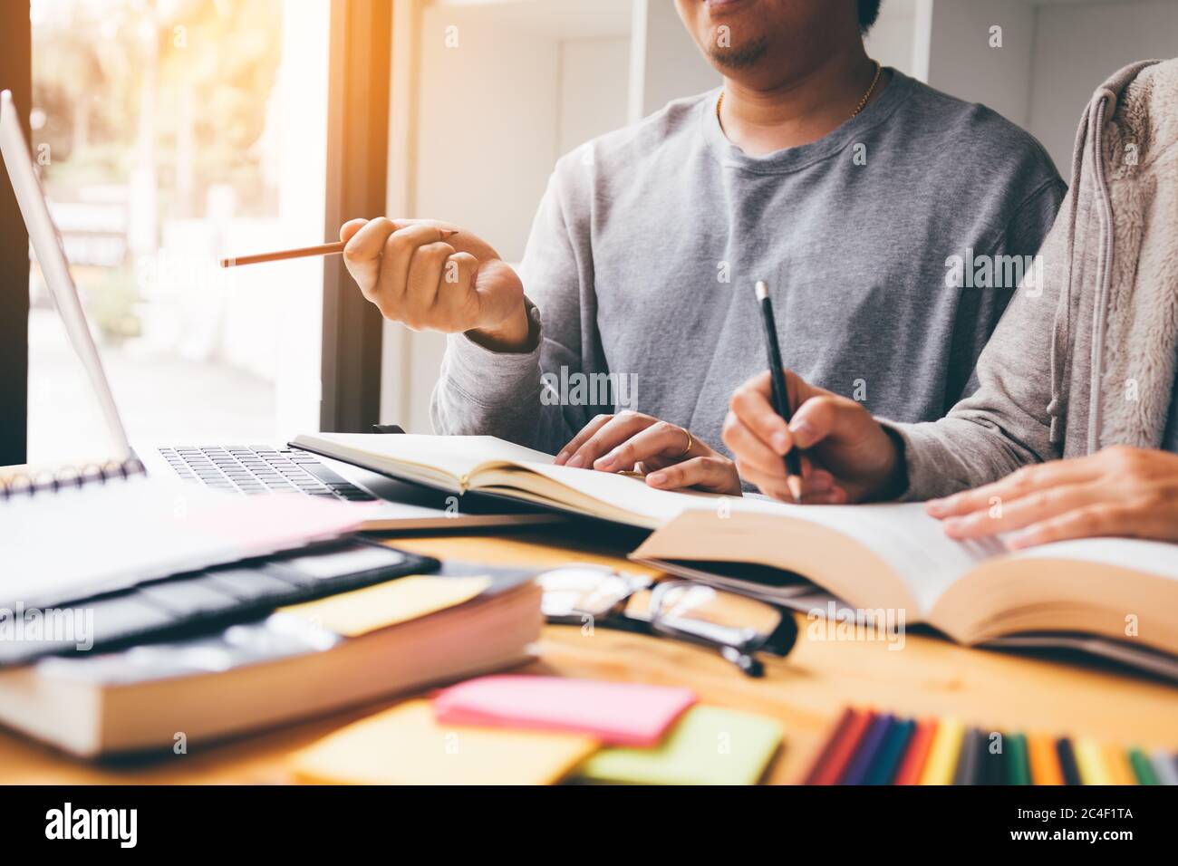Asian young university students studying together sitting at desk in ...