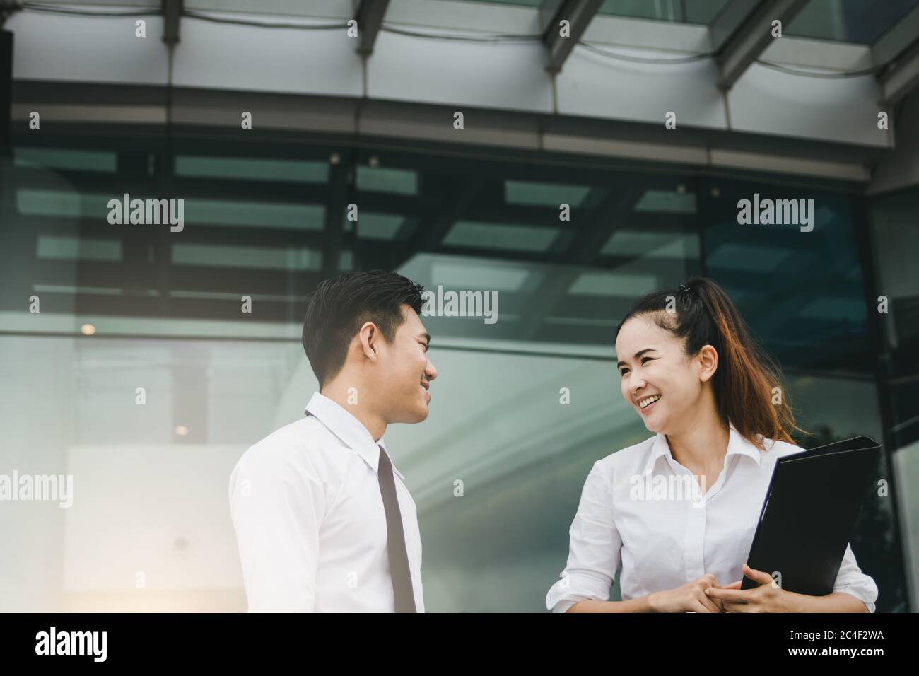 Two business people talking together at office building Stock Photo - Alamy
