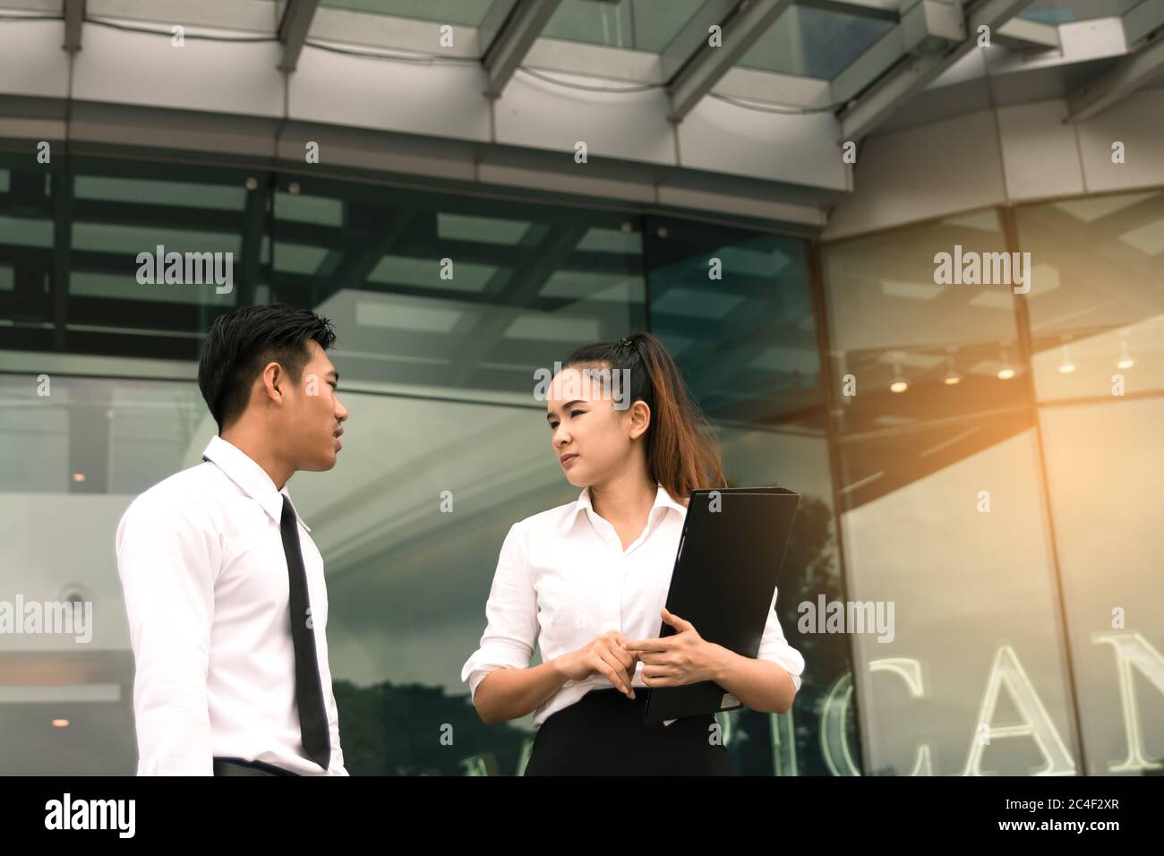 Two business people talking together at office building Stock Photo - Alamy