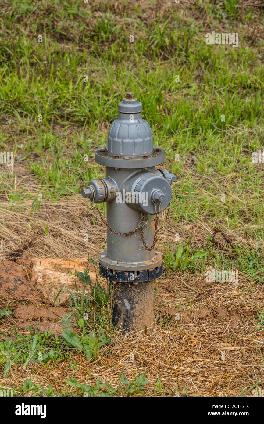 A repaired gray fire hydrant above ground in dirt and grass outdoors ...