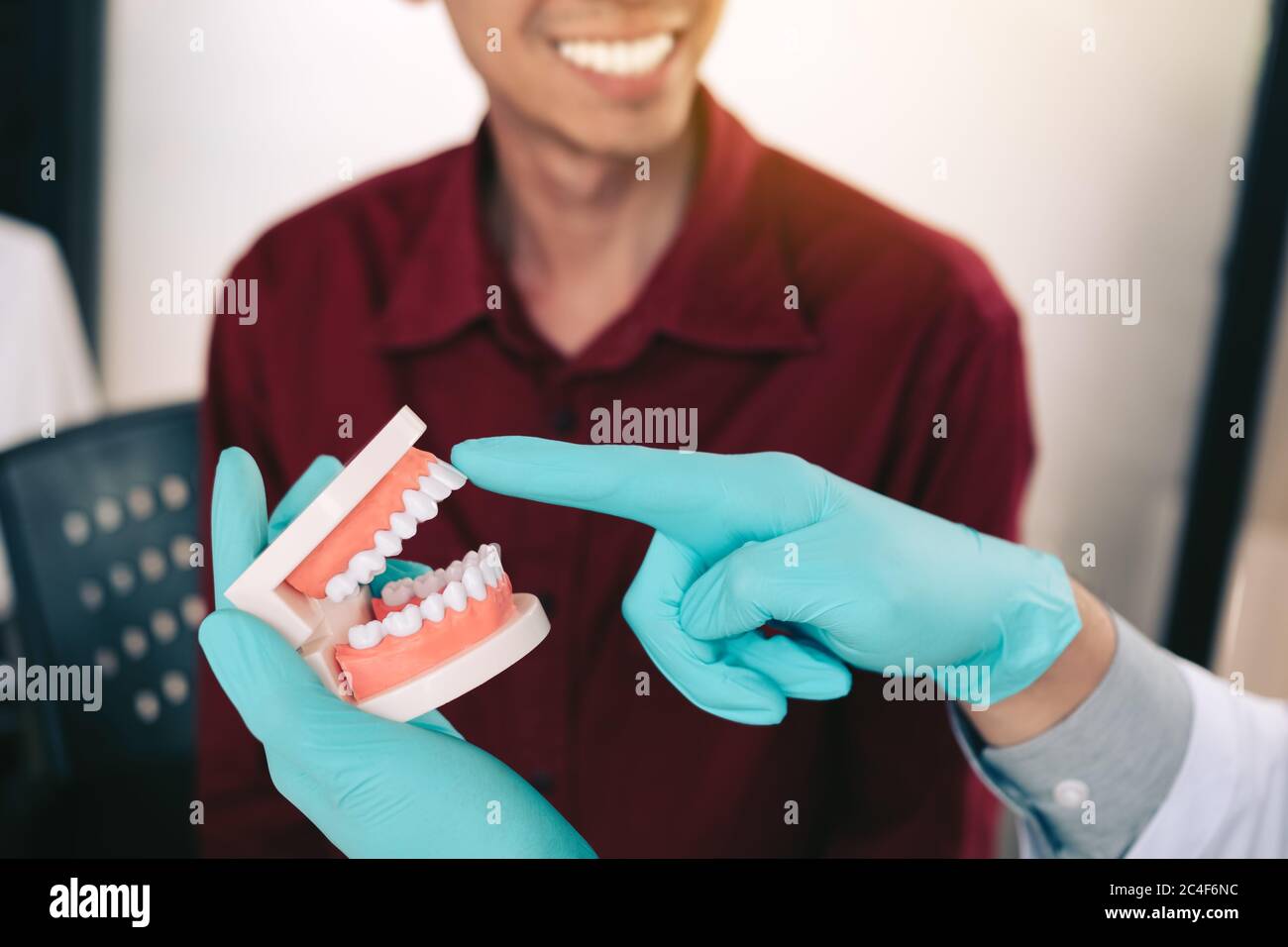 Asian dentist pointing to the dentures and is describing the problem of ...