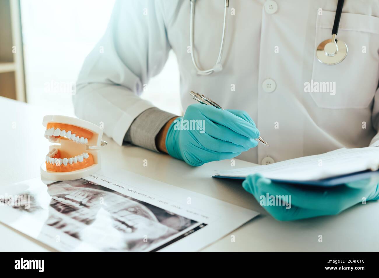 Dentist writing analysis and making note report to patient in office ...
