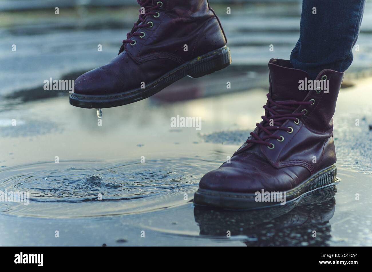 Female boots dripping water in rain puddle Stock Photo - Alamy