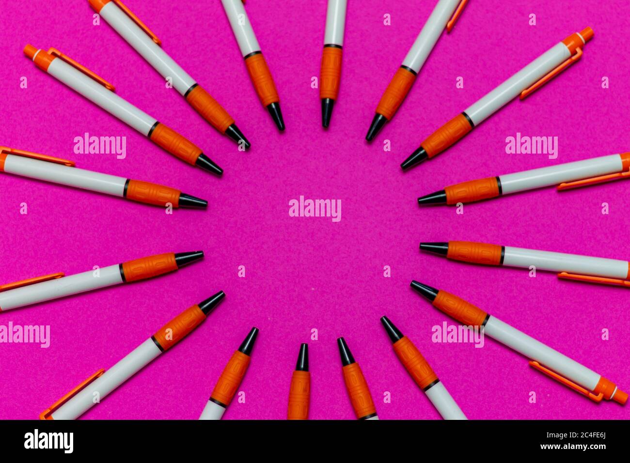 Overhead shot of identical orange and white pens creating a circle on a ...