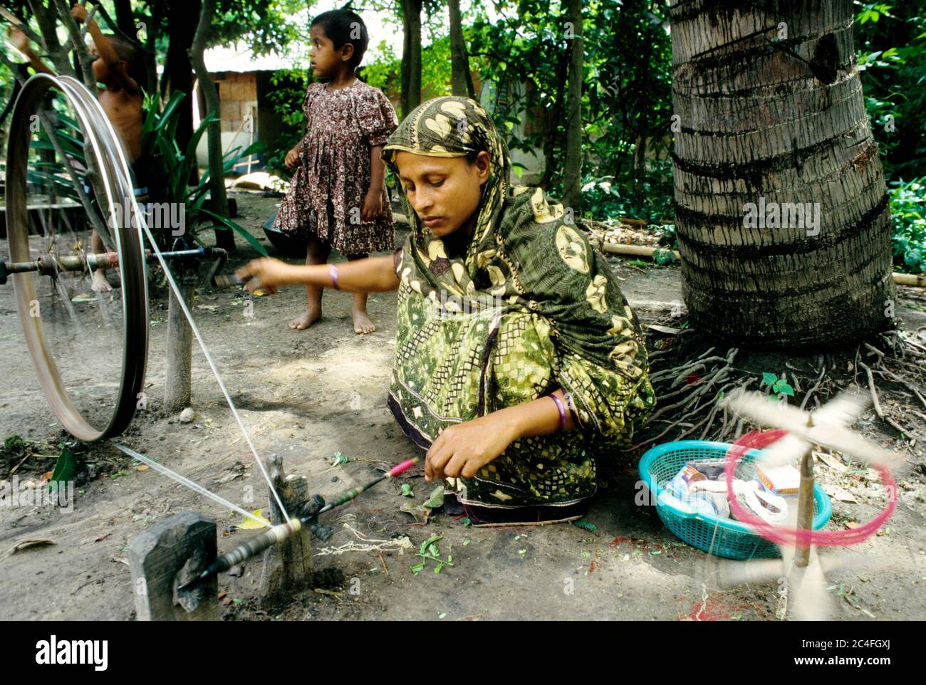 A woman works with a cotton spool. Weaving is an age-old tradition of ...