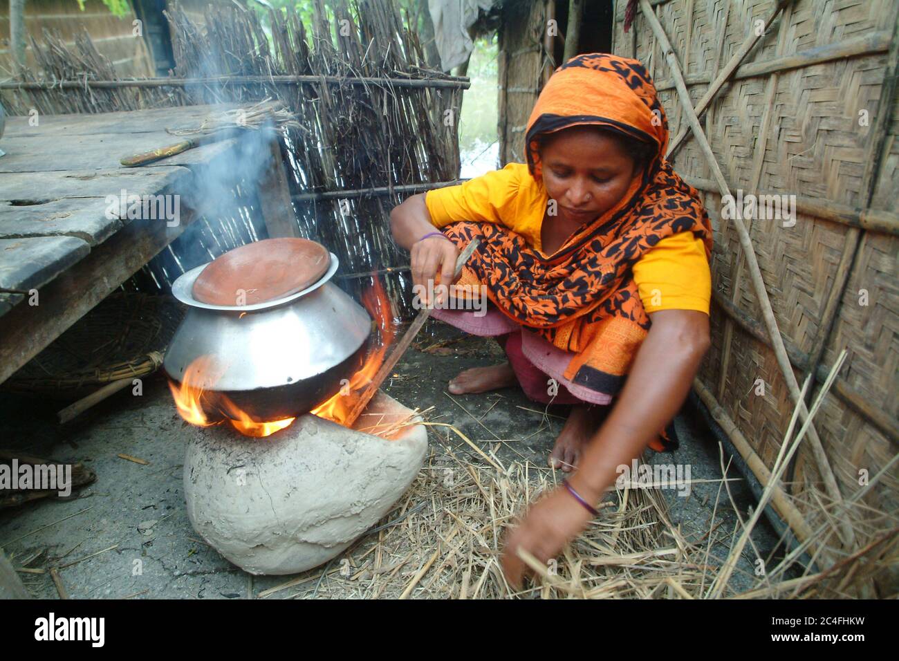 A rural woman cooking rice on an earthen oven in the flood affected ...