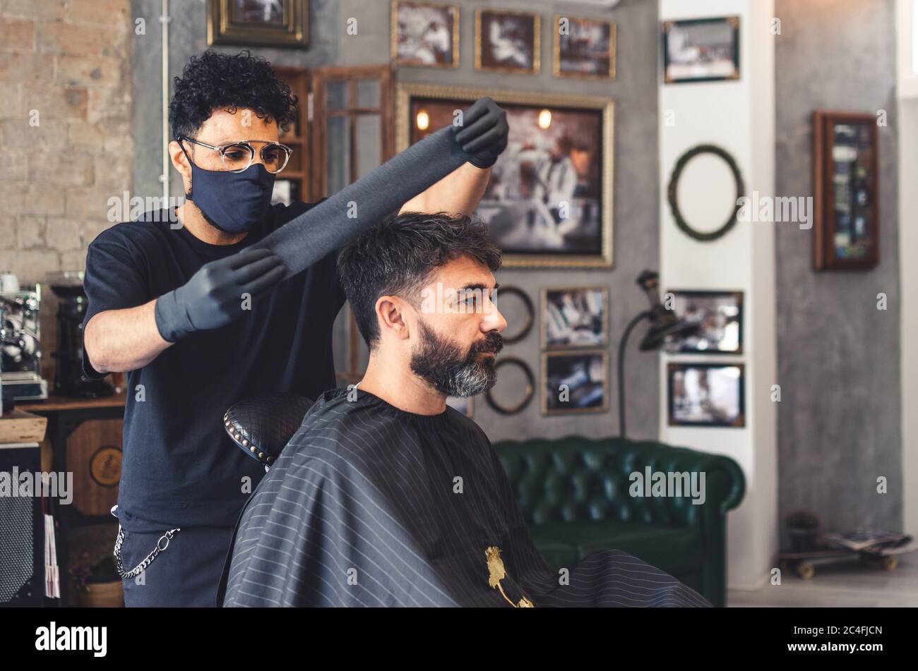 Mulatto barber preparing neck cover paper in a barbershop. Client with ...