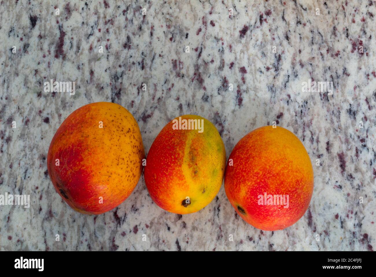 top view of three colorful mangoes on a light colored background Stock ...