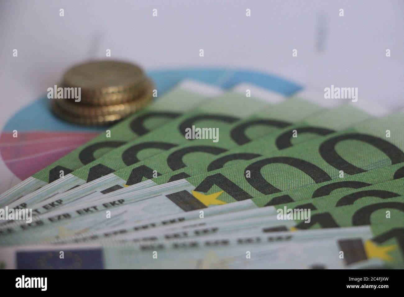 Stack of coins laying on 100 euro bills. with financial report graph ...