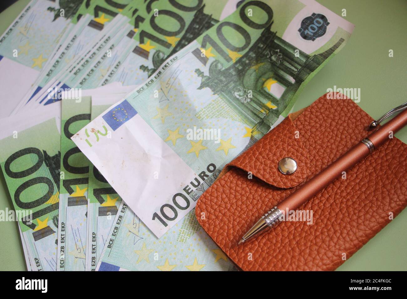 Many 100 Euro bills, brown leather wallet and luxury pen on mint ...