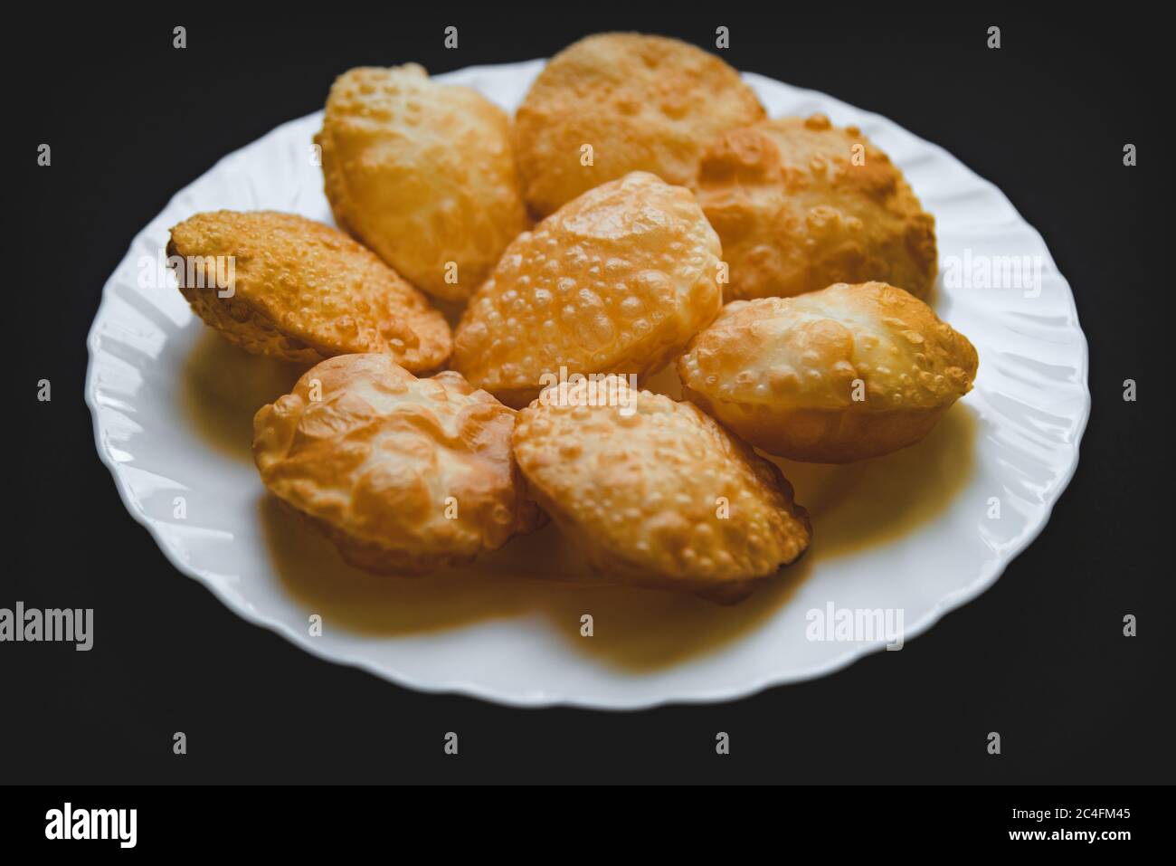 Traditional South Indian poori with black background on a white plate ...