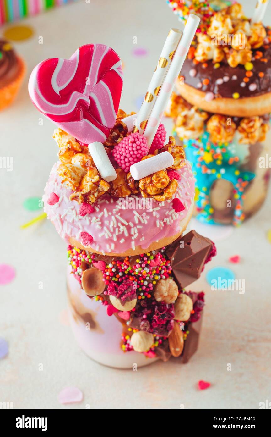 Raspberry freak shake topping with donut, caramel popcorn and sweets on ...