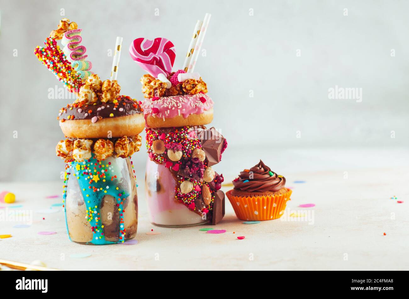Two freak shakes topping with donuts, popcorn and sweets on party ...