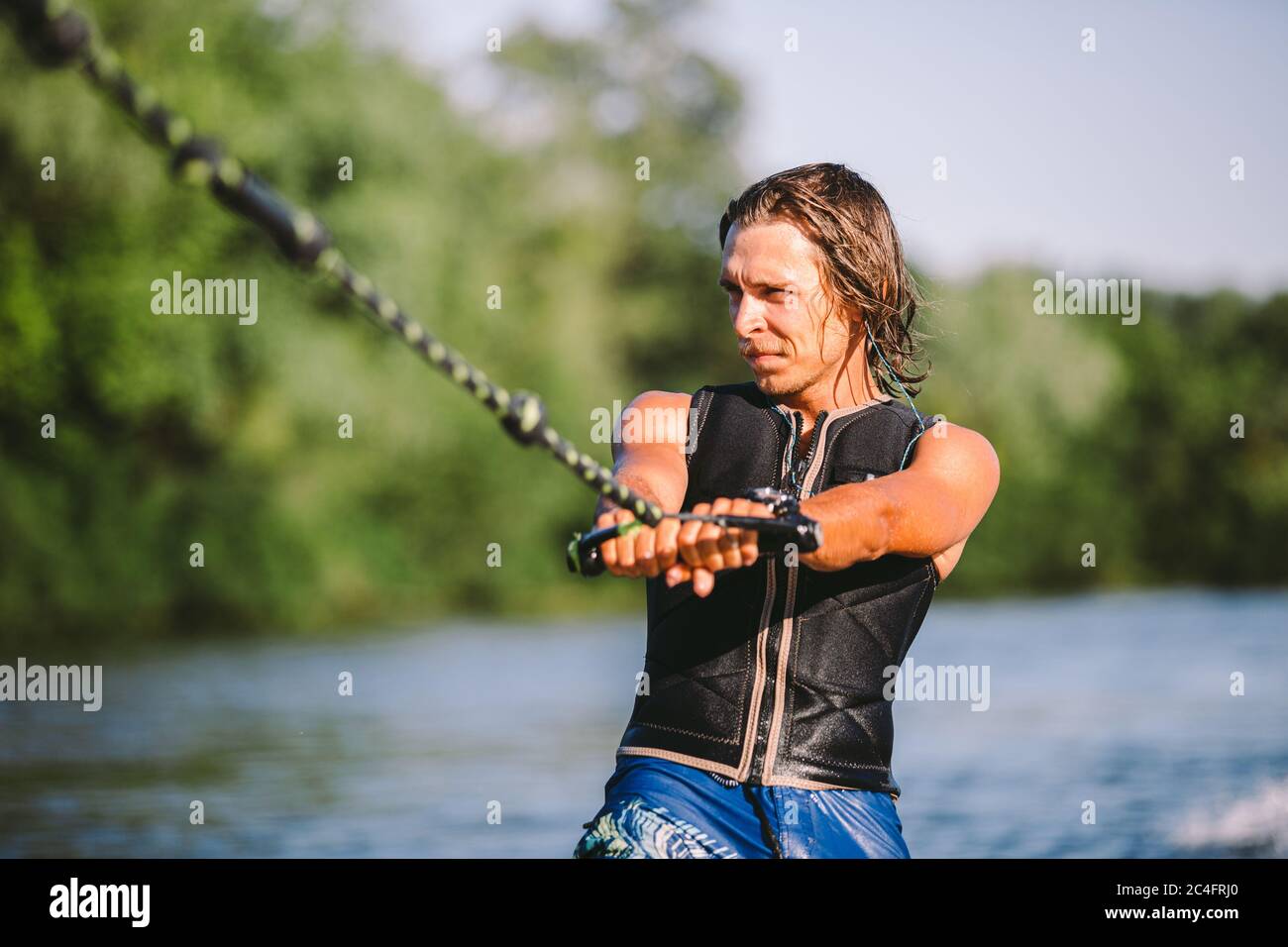 Beautiful long haired blond wakesurf in vest on board along waves of ...