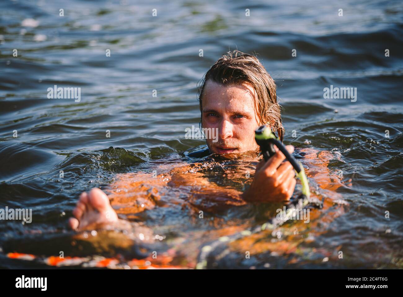 Beautiful long haired blond wakesurf in vest on board along waves of ...