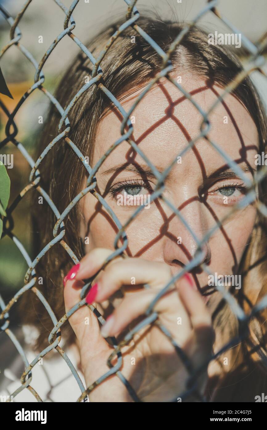 Close-up. The face of a young girl behind a metal fence Stock Photo - Alamy